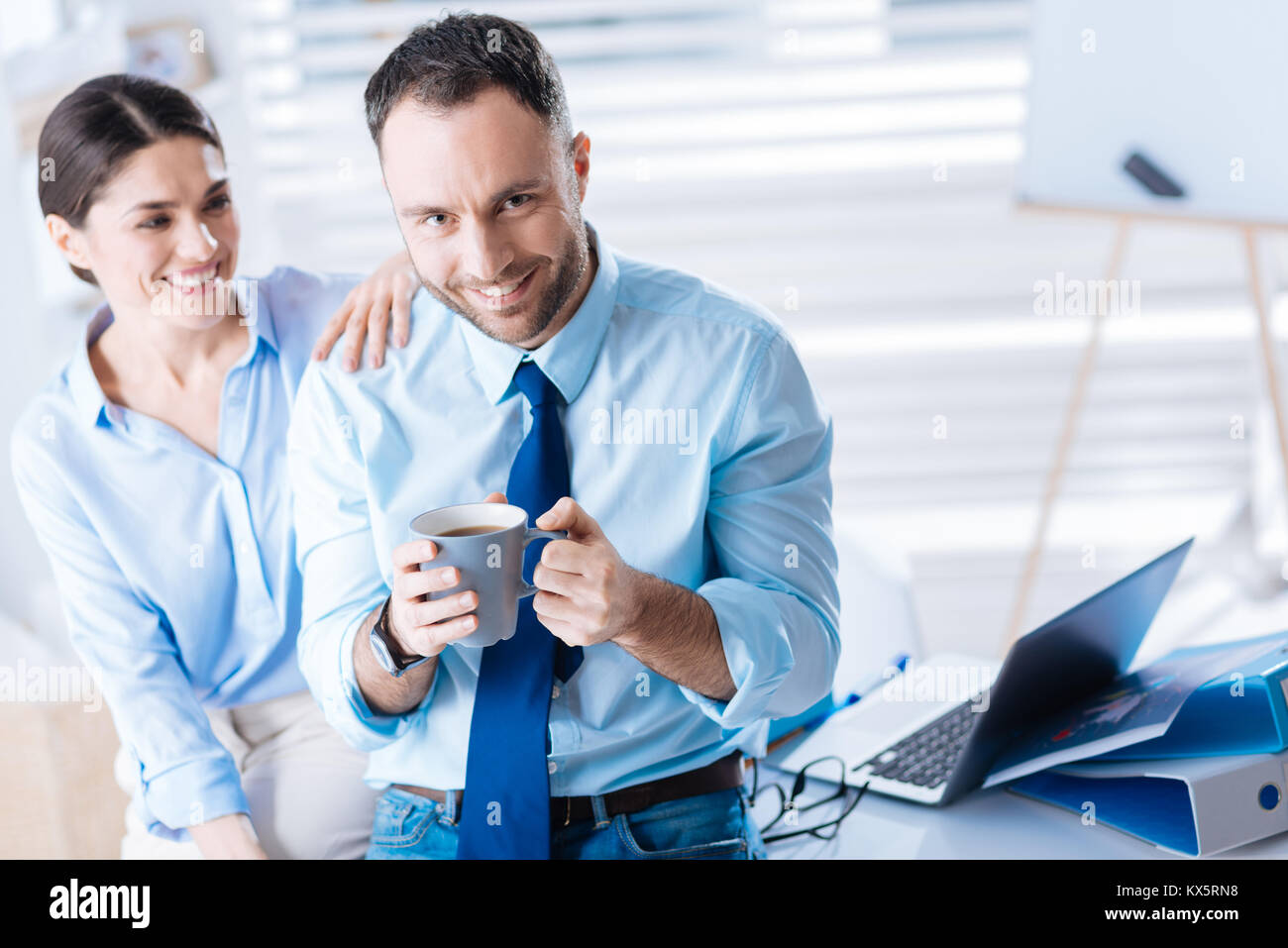 Positive colleagues smiling while being together in their light office ...