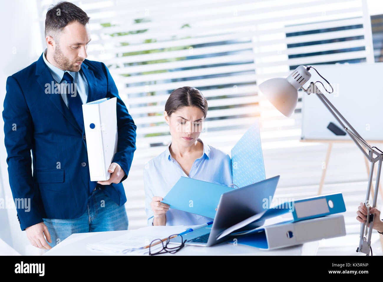 Smart woman looking at the documents while her colleague waiting Stock ...