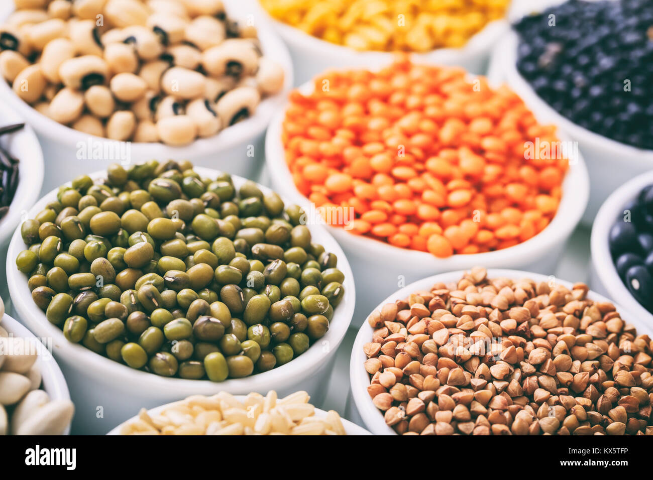 Various raw legumes and rice in white bowls Stock Photo - Alamy