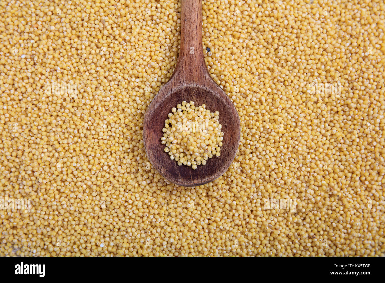 Wooden spoon on raw millet background Stock Photo - Alamy