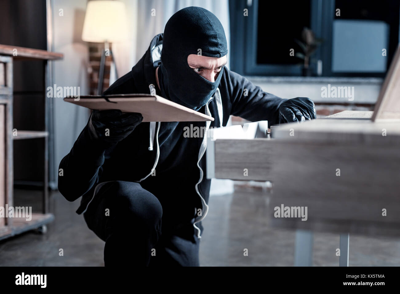 Masked robber searching what to steal Stock Photo - Alamy