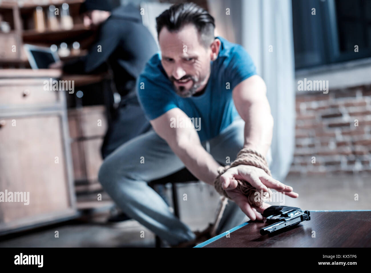Intimidated man trying to reach the pistol Stock Photo - Alamy