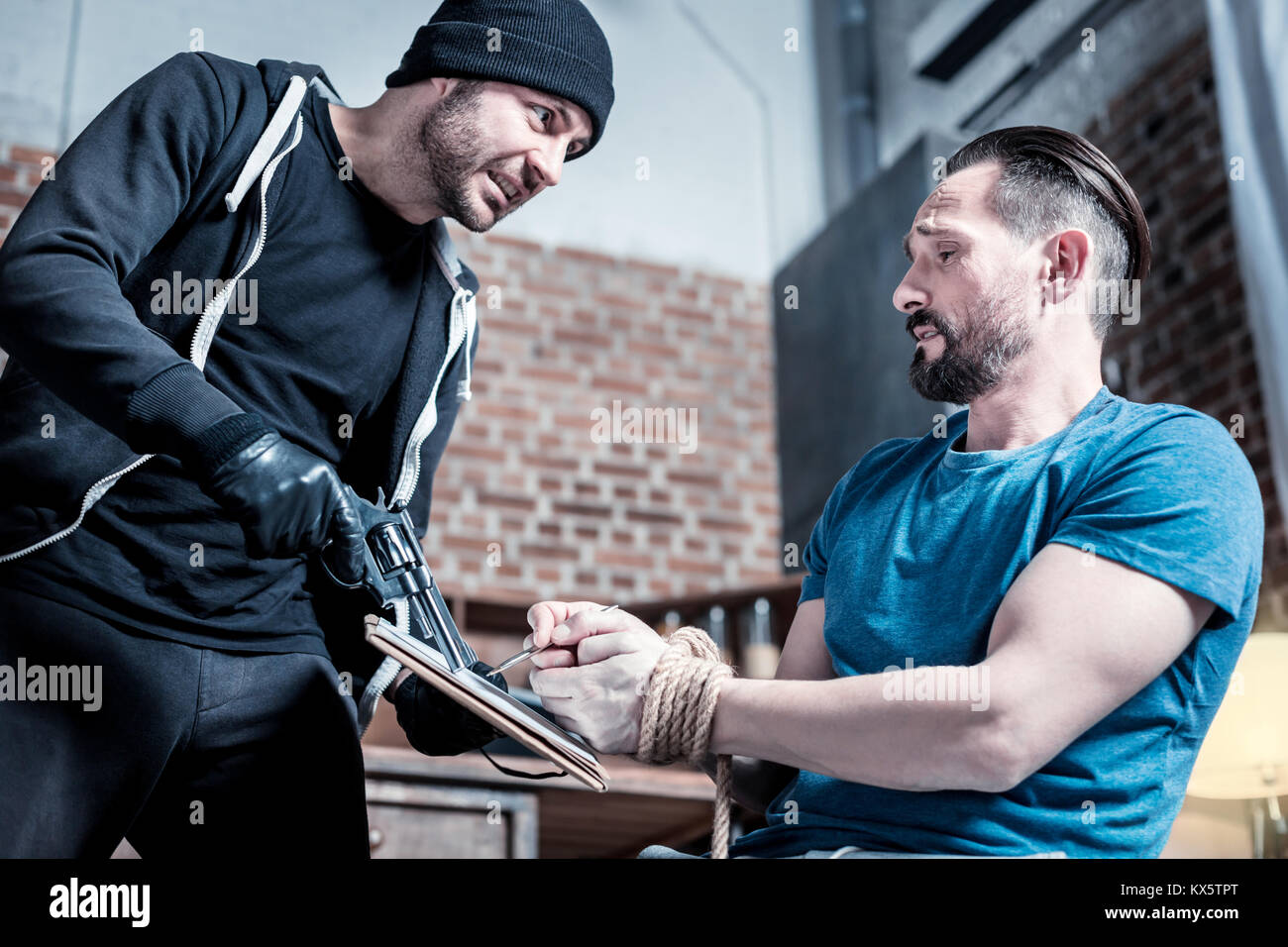 Angry criminal making a man sign a contract Stock Photo - Alamy