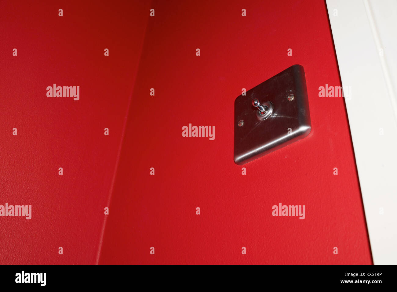 Low angle view of a light switch against a red wall Stock Photo - Alamy