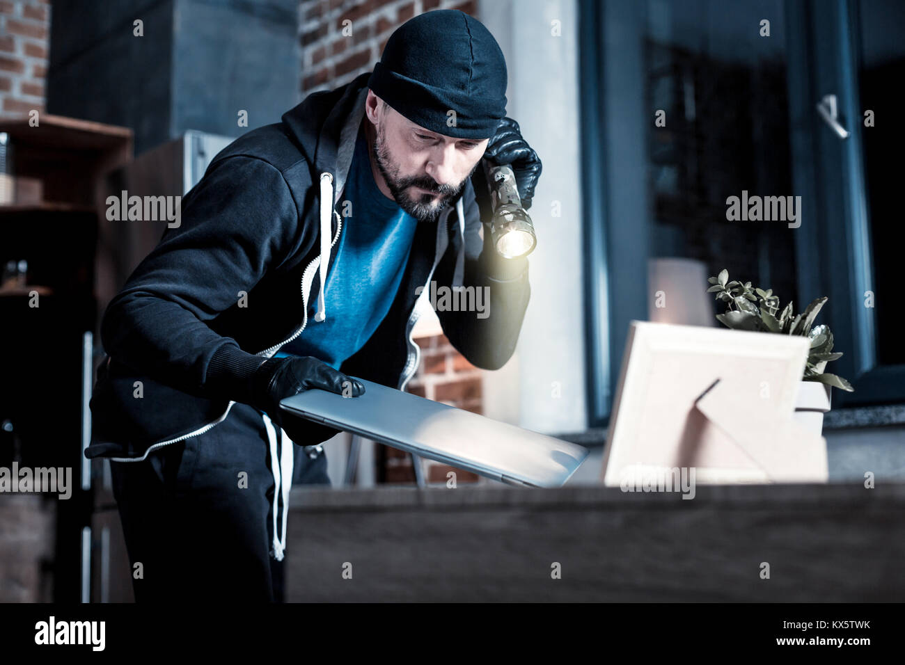 Determined bearded thief stealing a laptop Stock Photo - Alamy