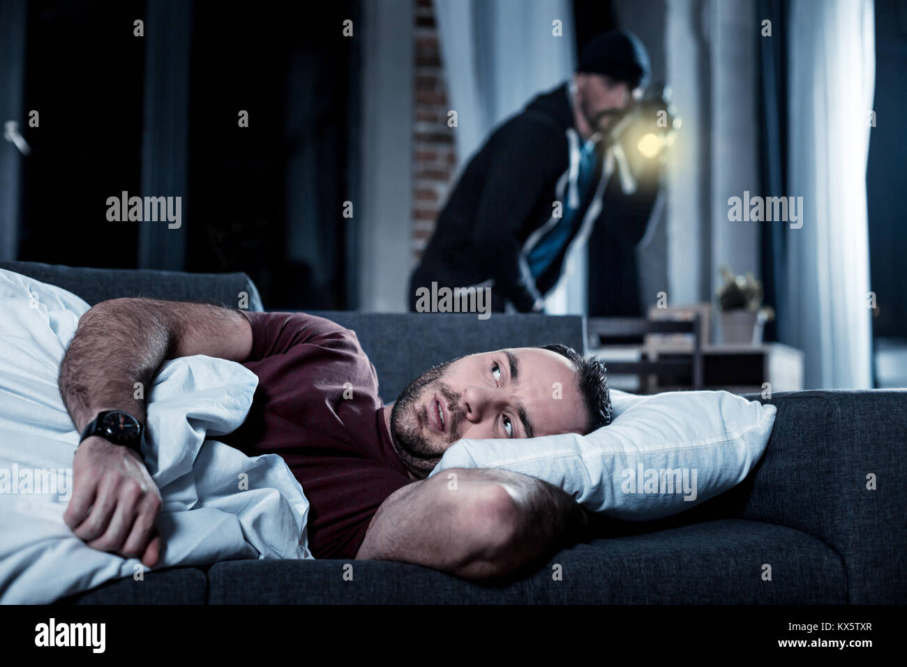 Alarmed man waking up and hearing someone being inside Stock Photo - Alamy