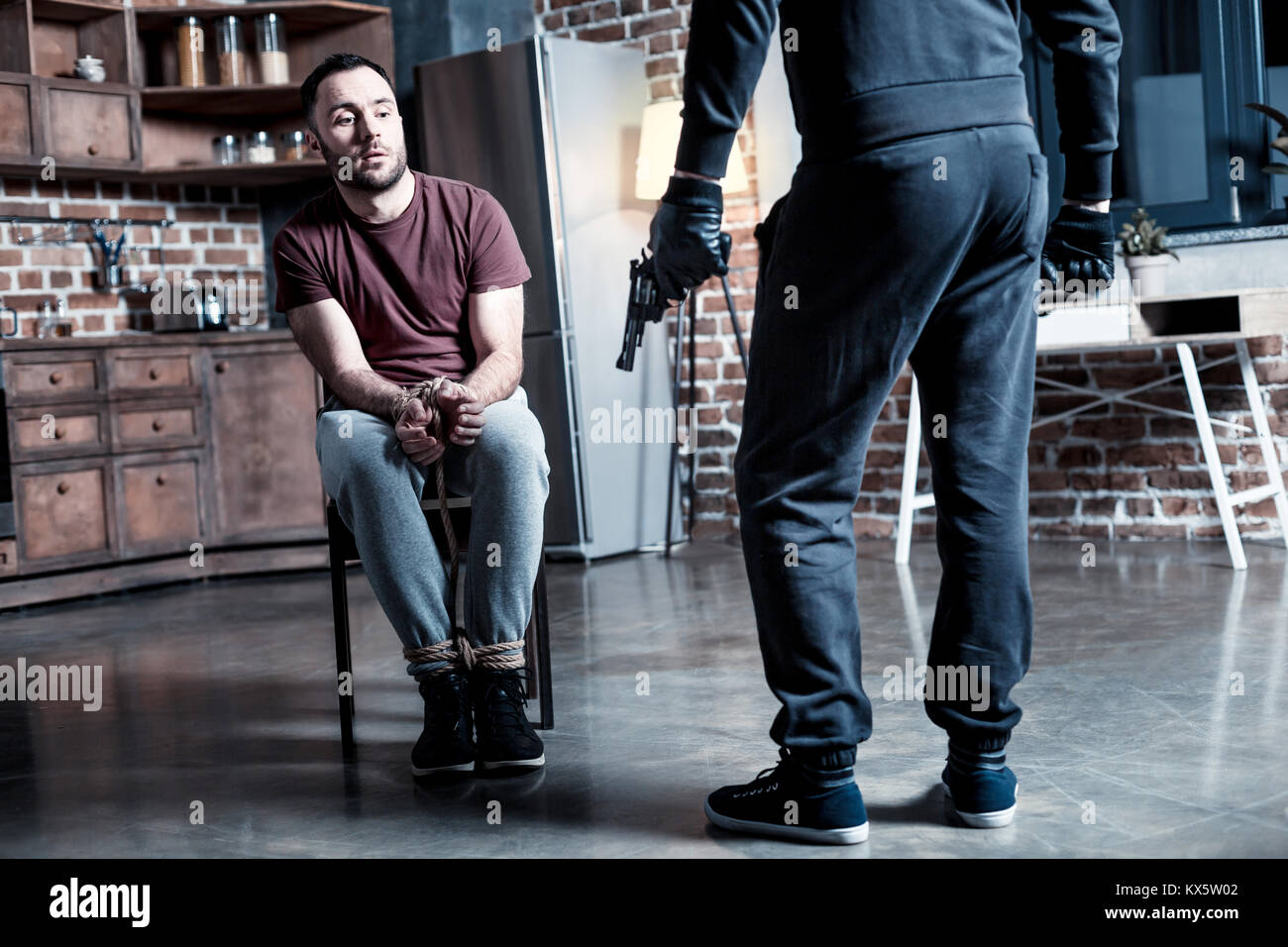 Intimidated man sitting in front of the killer Stock Photo - Alamy