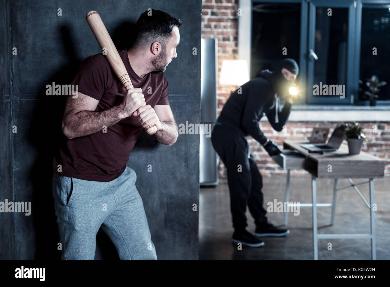 Frightened man hiding with a stick behind the wall Stock Photo - Alamy