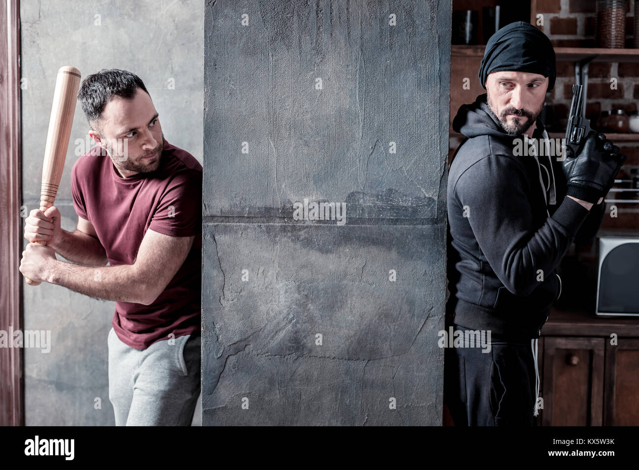 Determined man holding a stick and killer with a pistol Stock Photo - Alamy