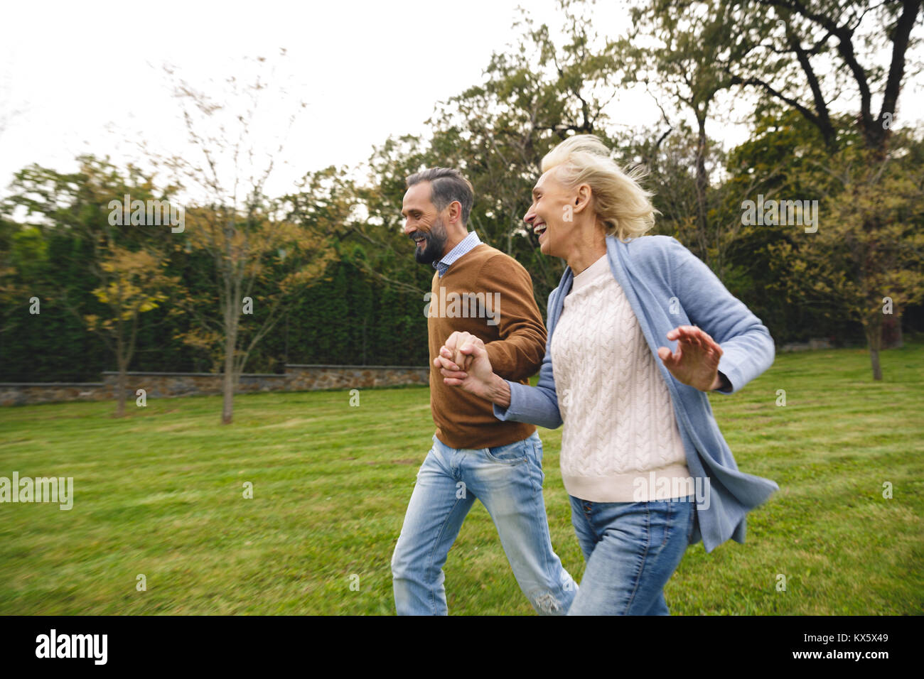 Happy mature couple holding hands while running together outdoors Stock ...