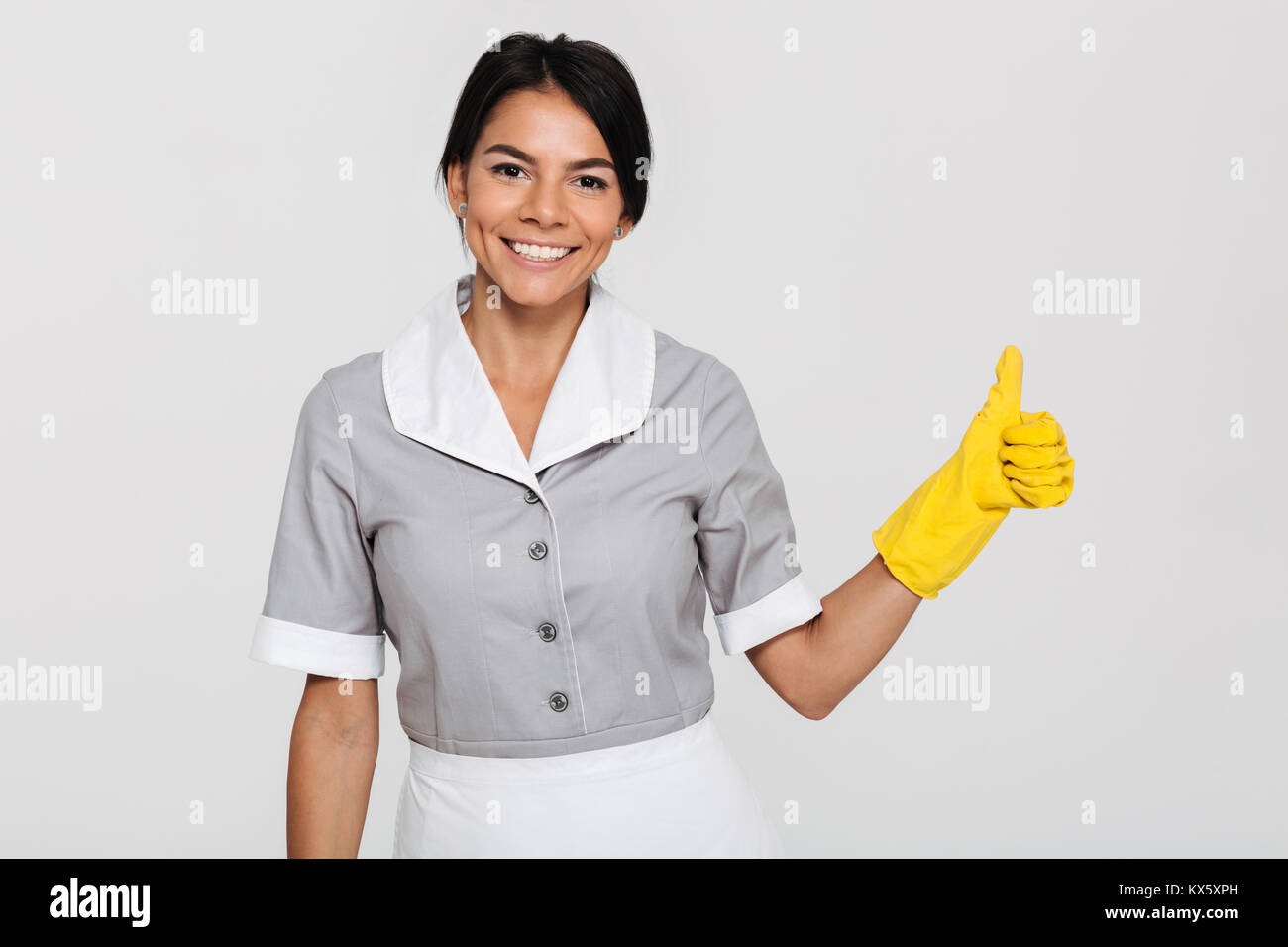 Portrait of a smiling cheery housekeeper dressed in uniform showing ...
