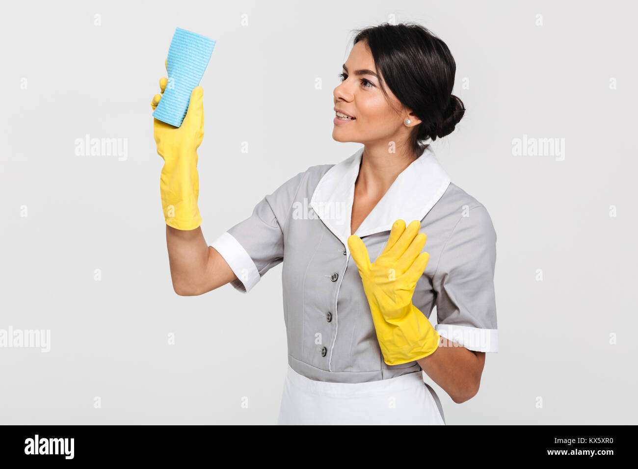 Portrait of a smiling cheery housekeeper dressed in uniform holding a ...
