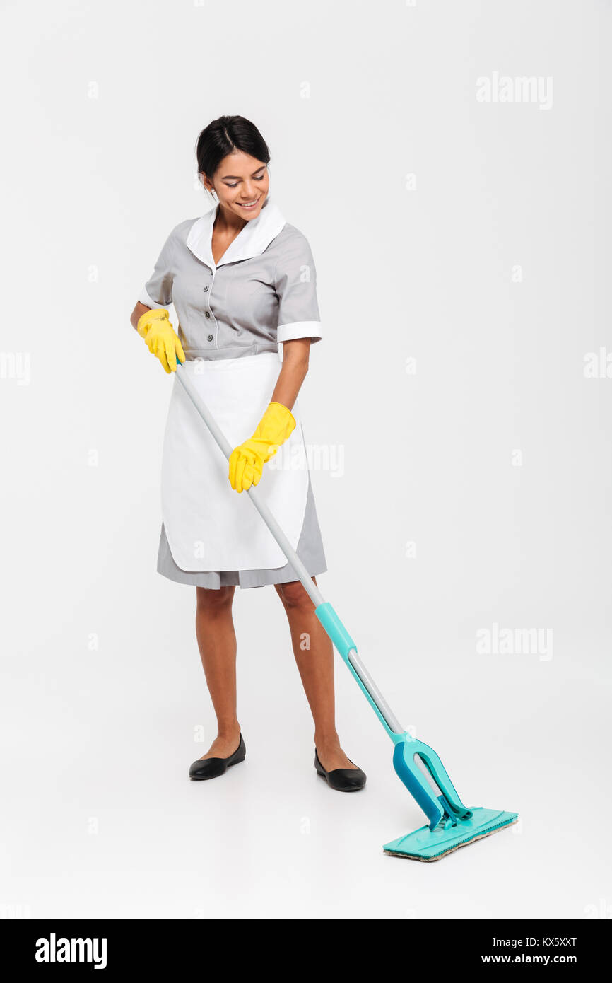 Full length photo of happy housekeeper in uniform cleaning floor with ...