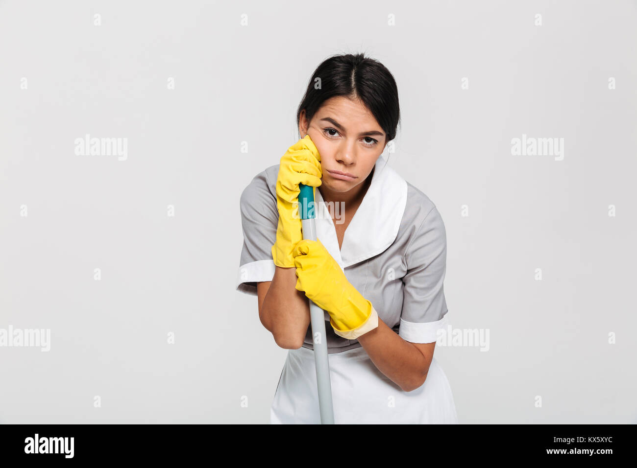 Close-up photo of tired housekeeper leaned on mop while standing and ...