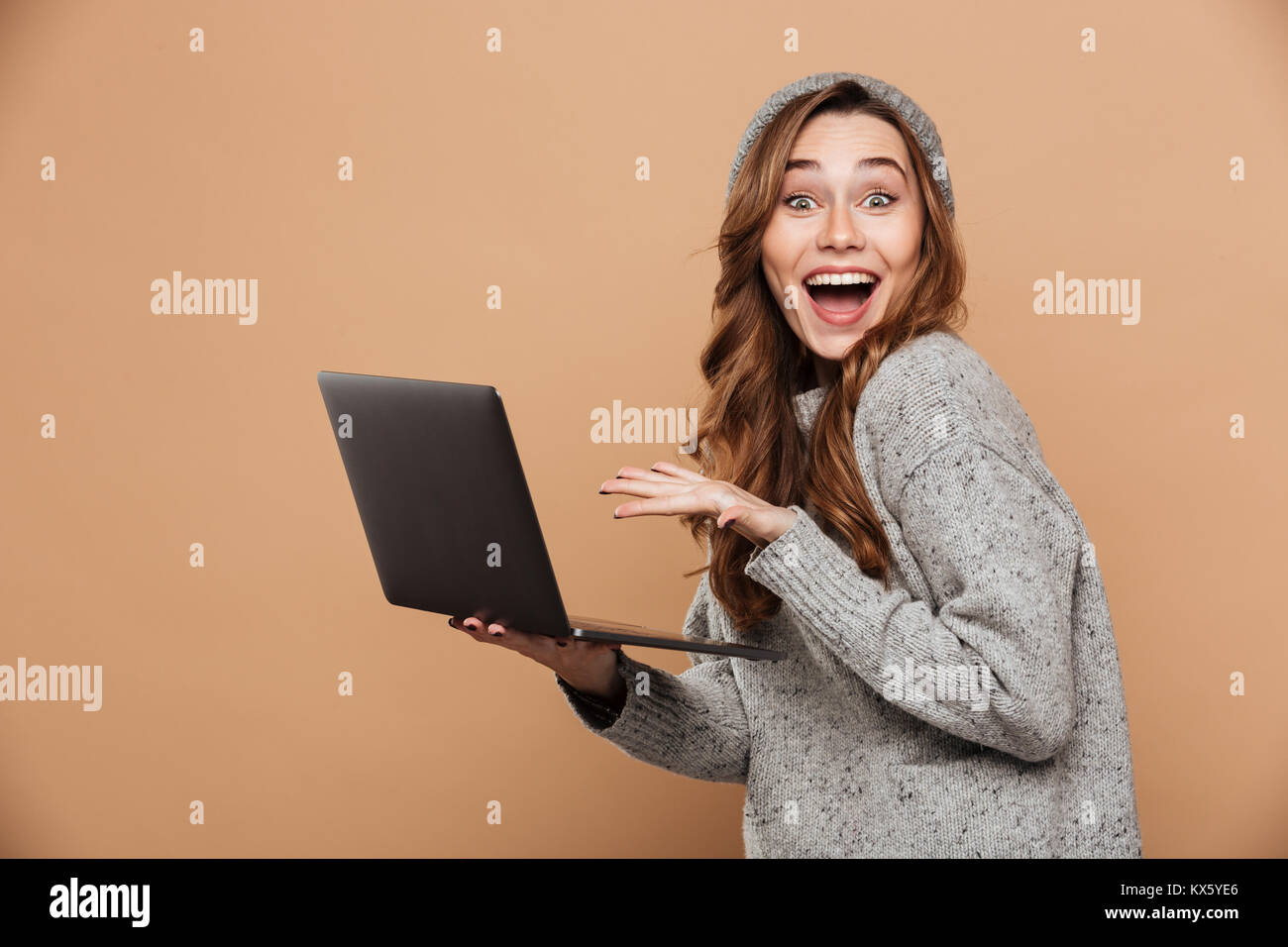 Happy exited attractive girl in warm clothes holding laptop computer ...