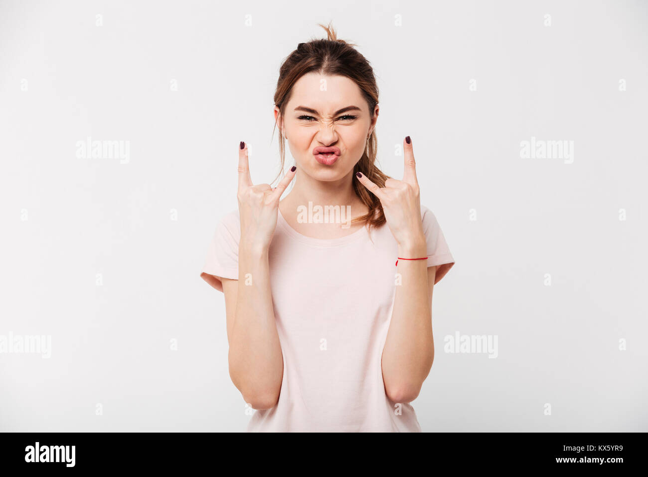Portrait of a funny pretty girl showing rock gesture with fingers ...