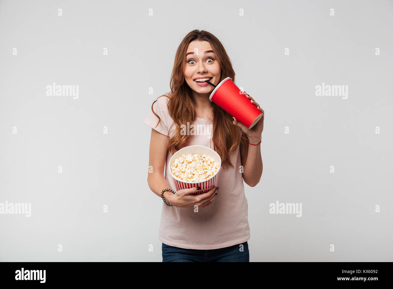 Portrait of an excited pretty girl holding plastic cup and popcorn ...