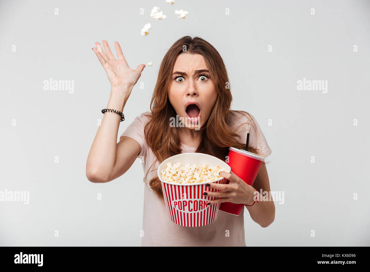 Portrait of a shocked pretty girl holding plastic cup and throwing out ...