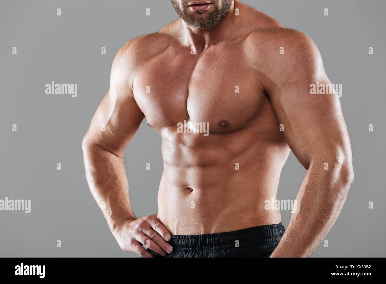 Cropped image of a muscular strong shirtless male bodybuilder standing ...