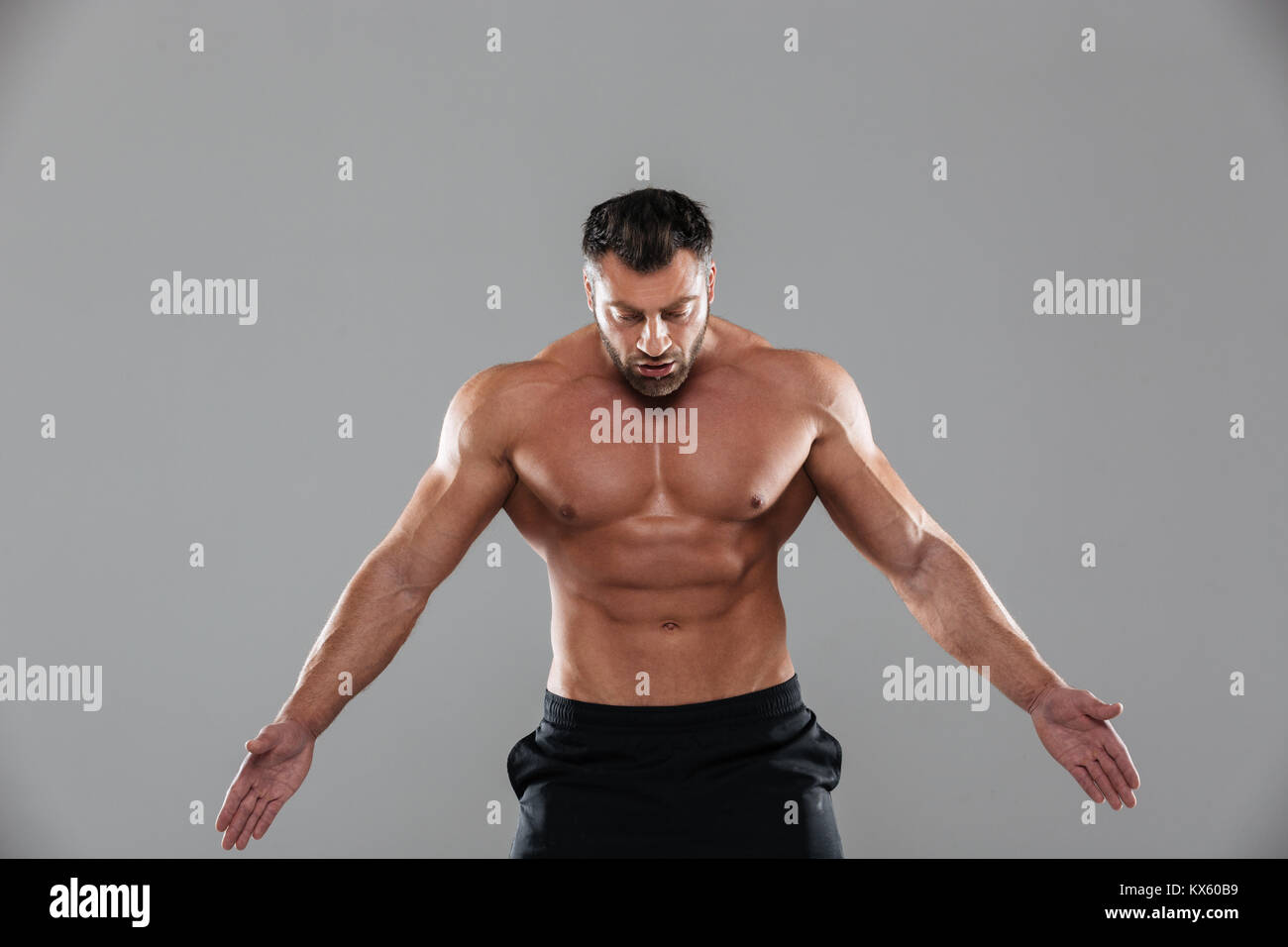 Portrait of a muscular strong shirtless male bodybuilder posing while ...