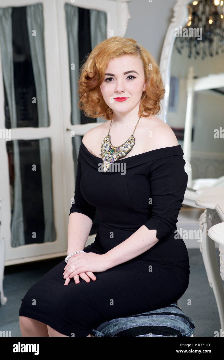 Pretty redheaded girl wearing a black dress in a boudoir location Stock ...