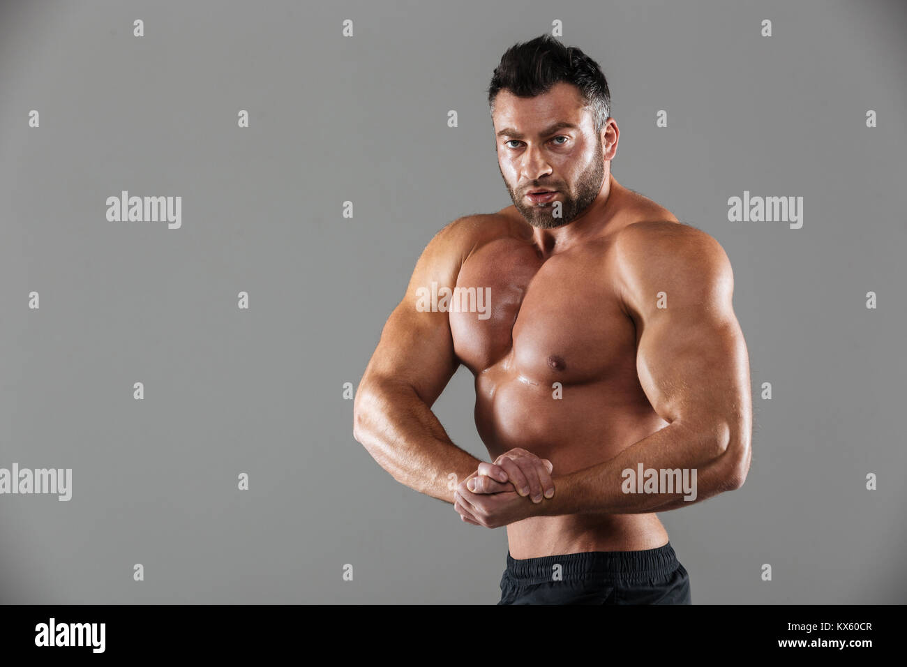 Portrait of a muscular confident shirtless male bodybuilder posing ...