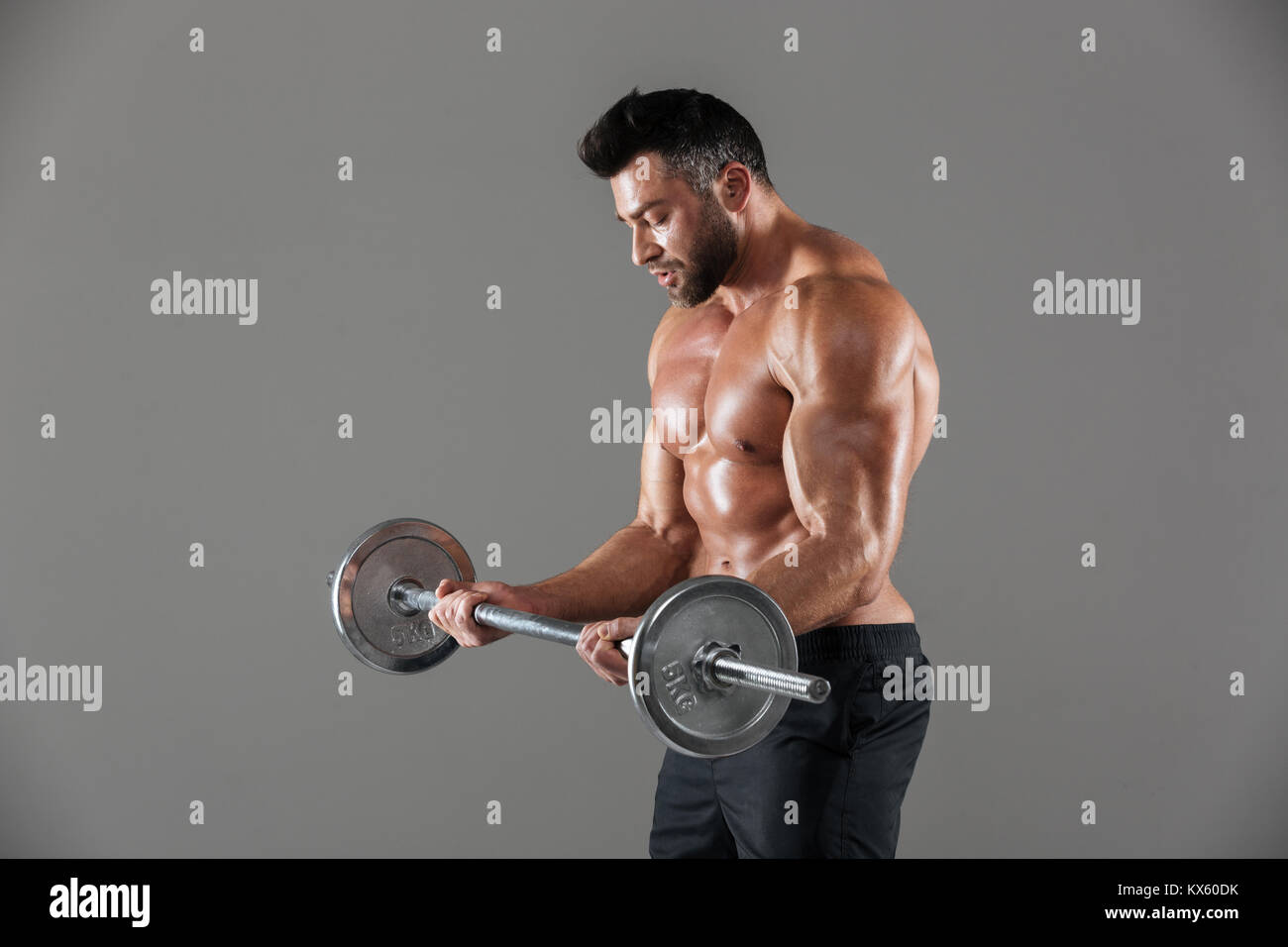 Side view of a concentrated strong shirtless male bodybuilder lifting ...