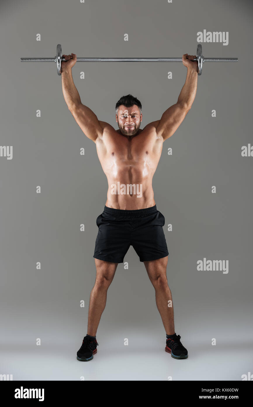 Full length portrait of a muscular serious shirtless male bodybuilder ...