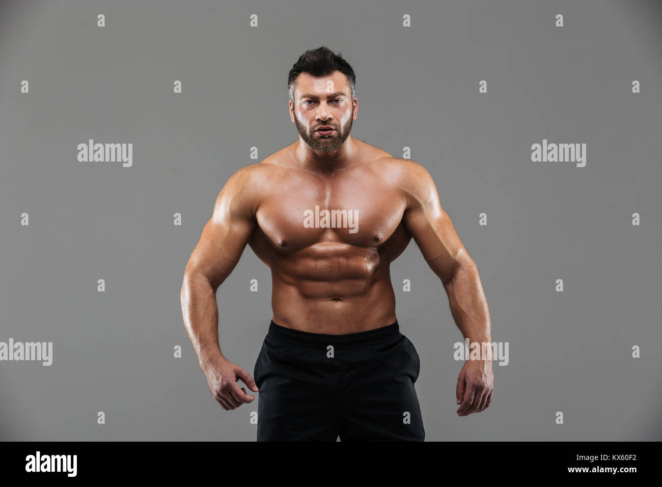 Portrait of a confident strong shirtless male bodybuilder standing and ...