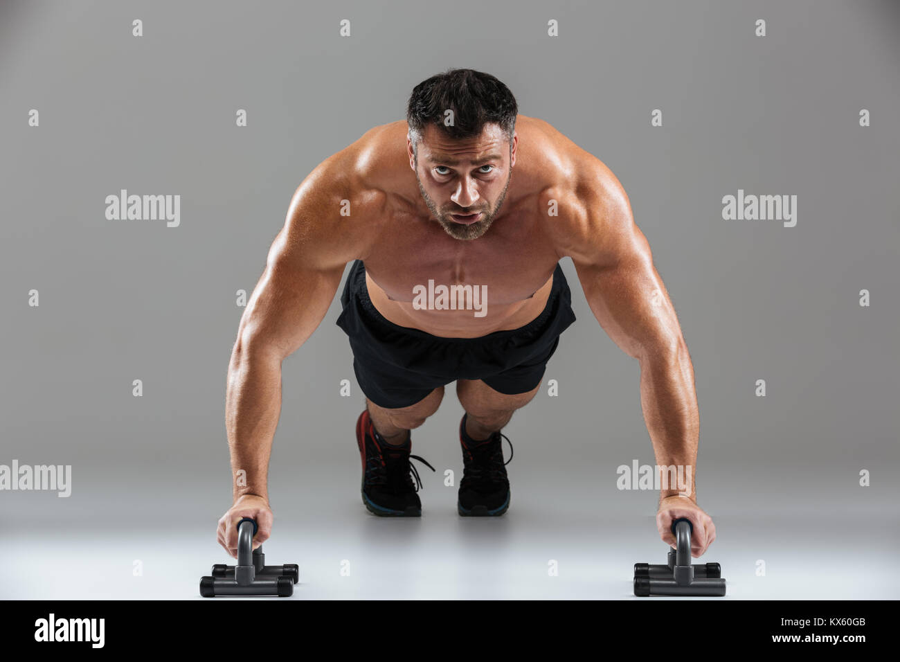 Close up portrait of a serious strong shirtless male bodybuilder doing ...