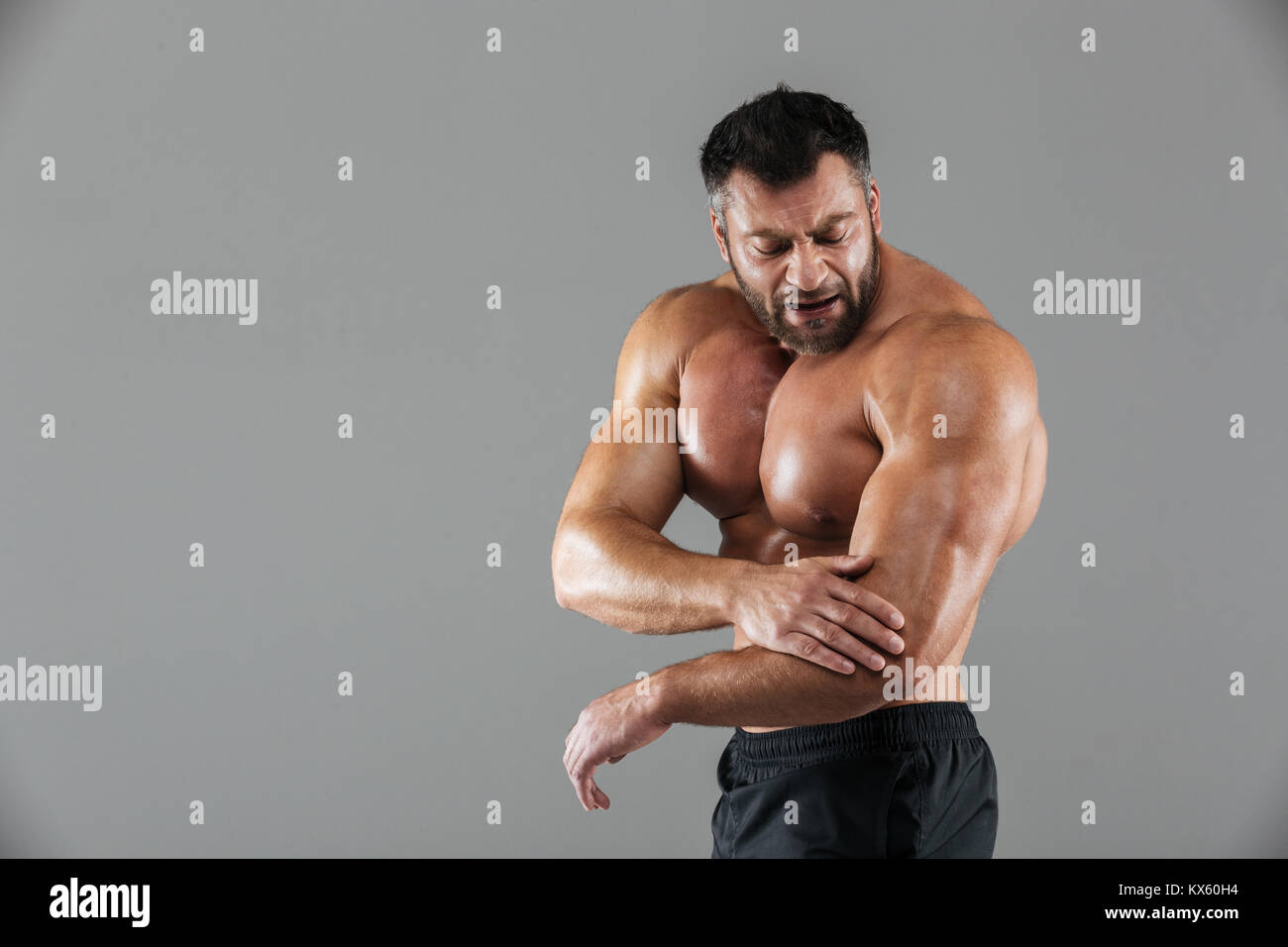 Portrait of a muscular male bodybuilder suffering from an elbow pain ...