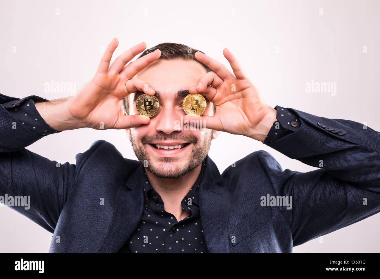Young handsome man cover eyes with bitcoin coins isolated on gray Stock ...