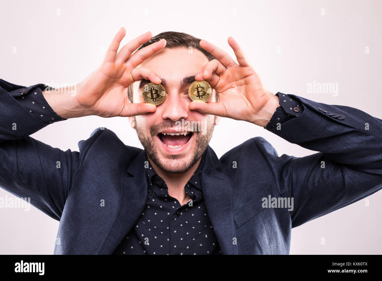 Young handsome man cover eyes with bitcoin coins isolated on gray ...