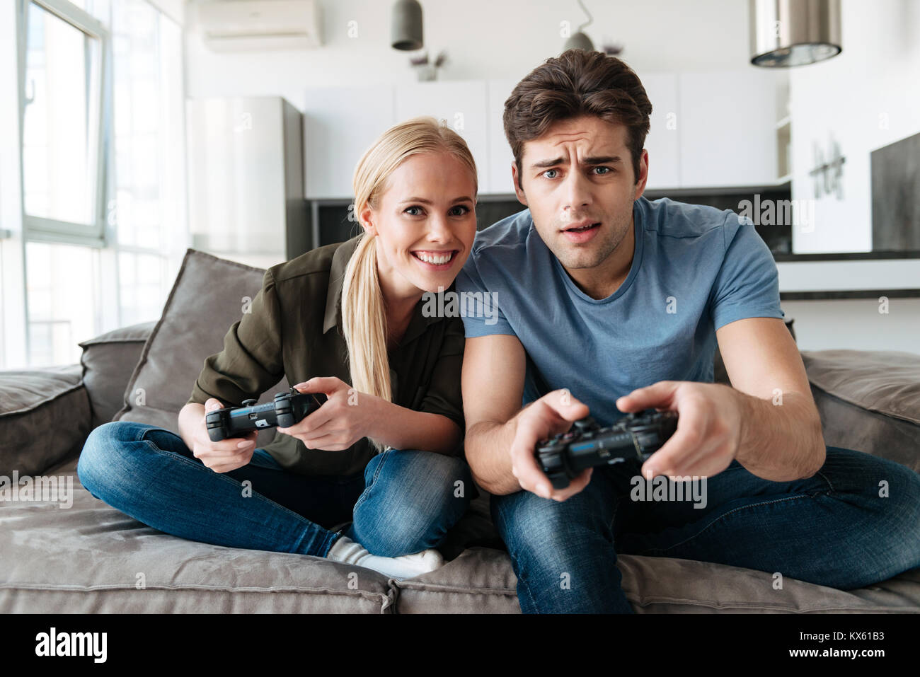 Young concentrated man and pretty woman playing video games in living ...