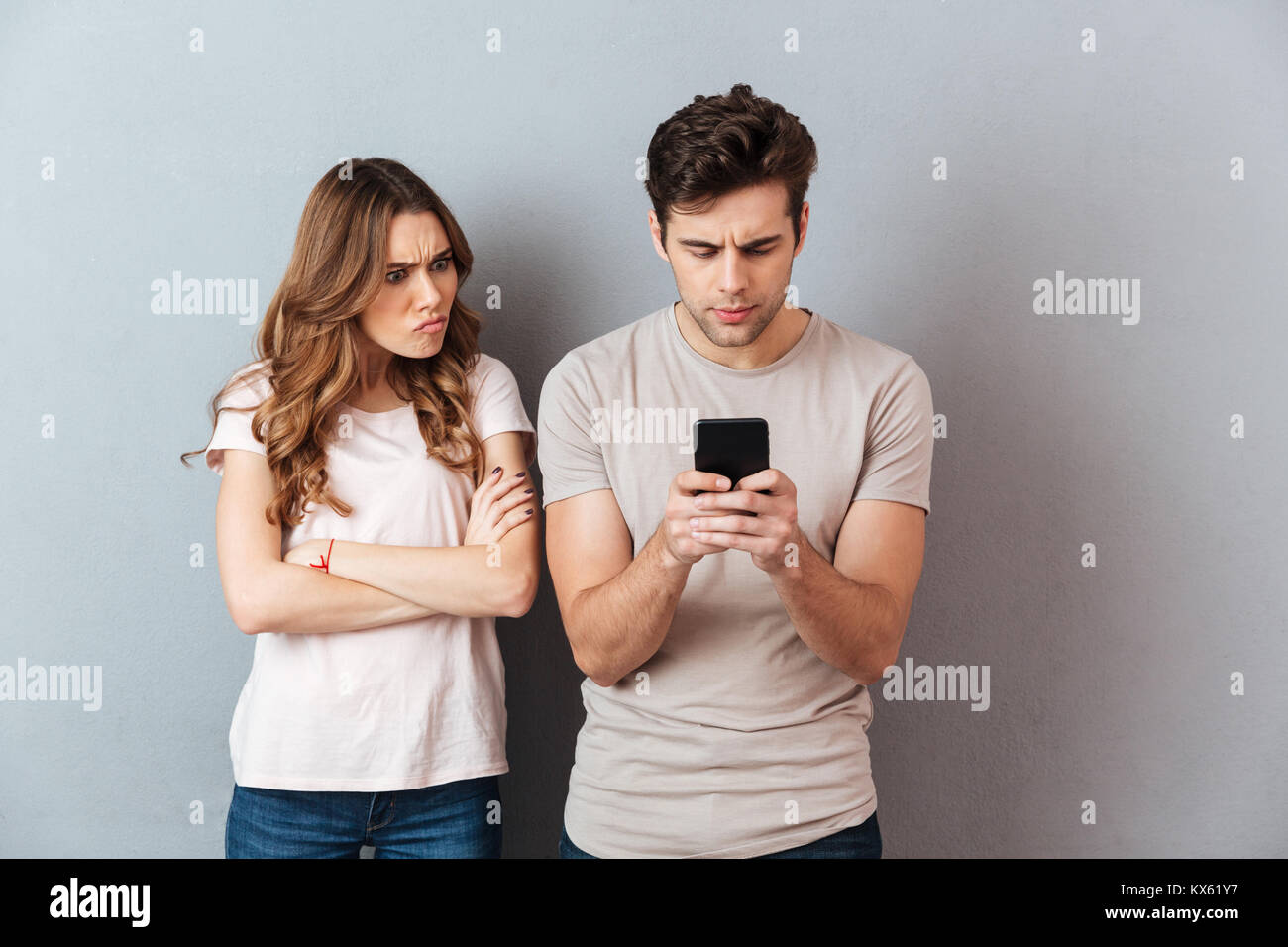 Portrait of a young couple standing with mobile phone, man is using ...