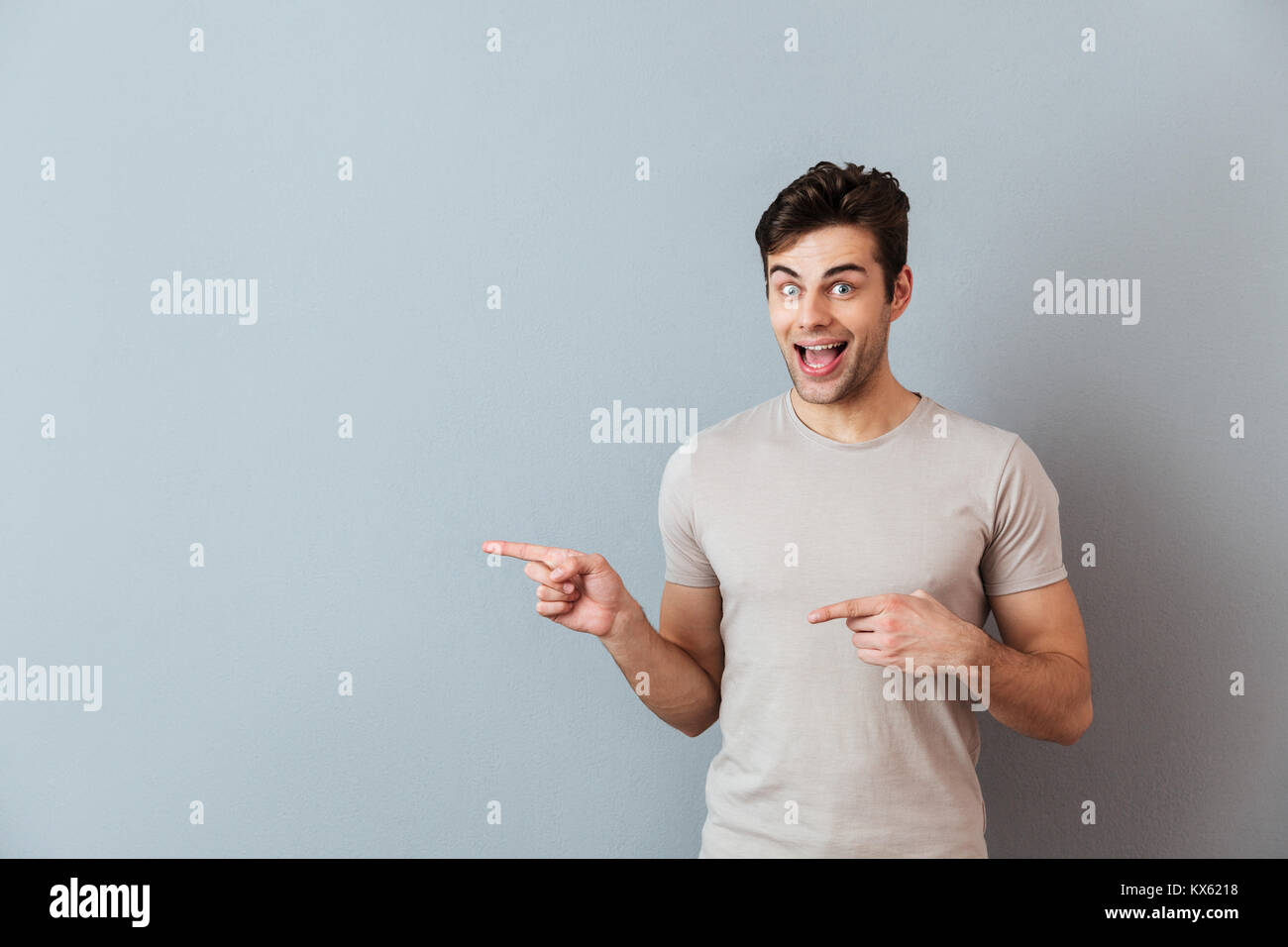 Portrait of an excited happy man pointing fingers away at copy space ...