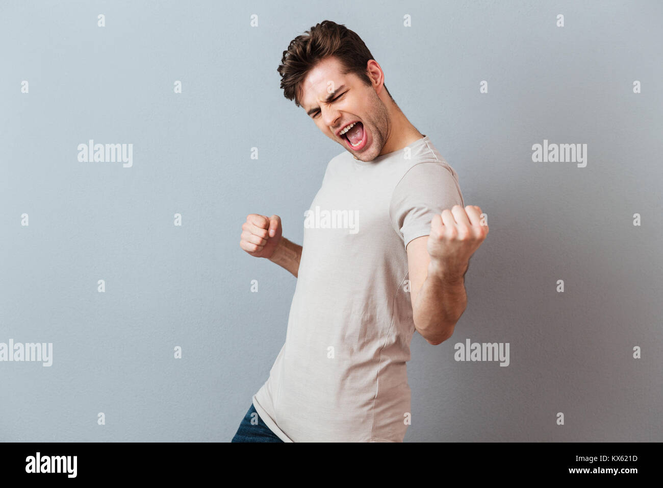 Portrait of a cheerful satisfied man celebrating success isolated over ...