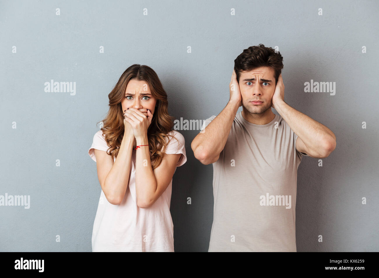 Portrait of an upset couple standing and covering ears and mouth ...