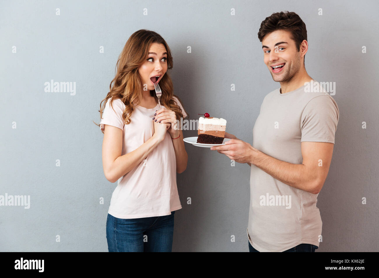 Portrait of a happy man giving his girlfriend a piece of cake on a ...