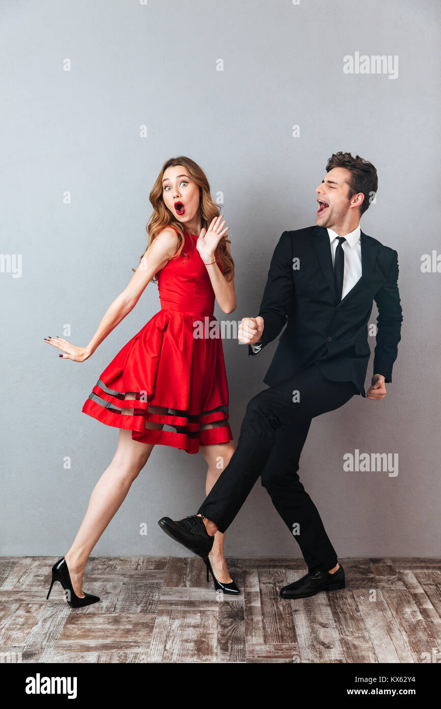 Full length portrait of a happy excited couple dressed in formal wear ...