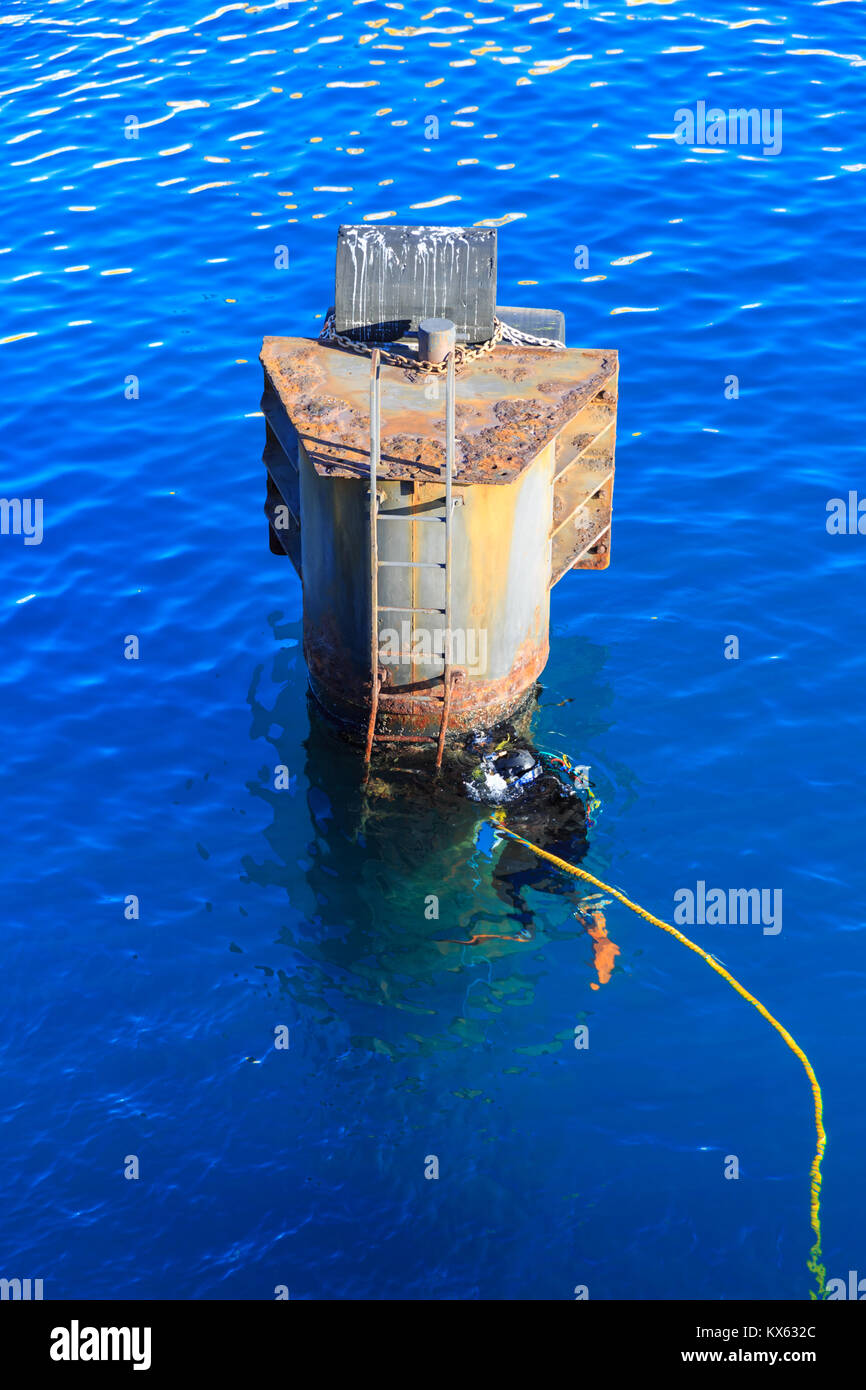 Diver exploring a rusty platform and diving in the azur blue water of ...