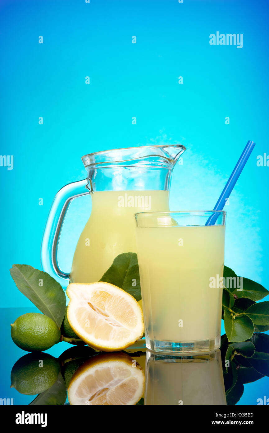 Pitcher of cool lemonade with glass on blue background Stock Photo - Alamy