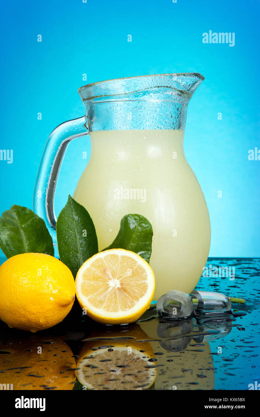 fresh cold lemonade in pitcher with mint leaf and ice cubes on blue ...