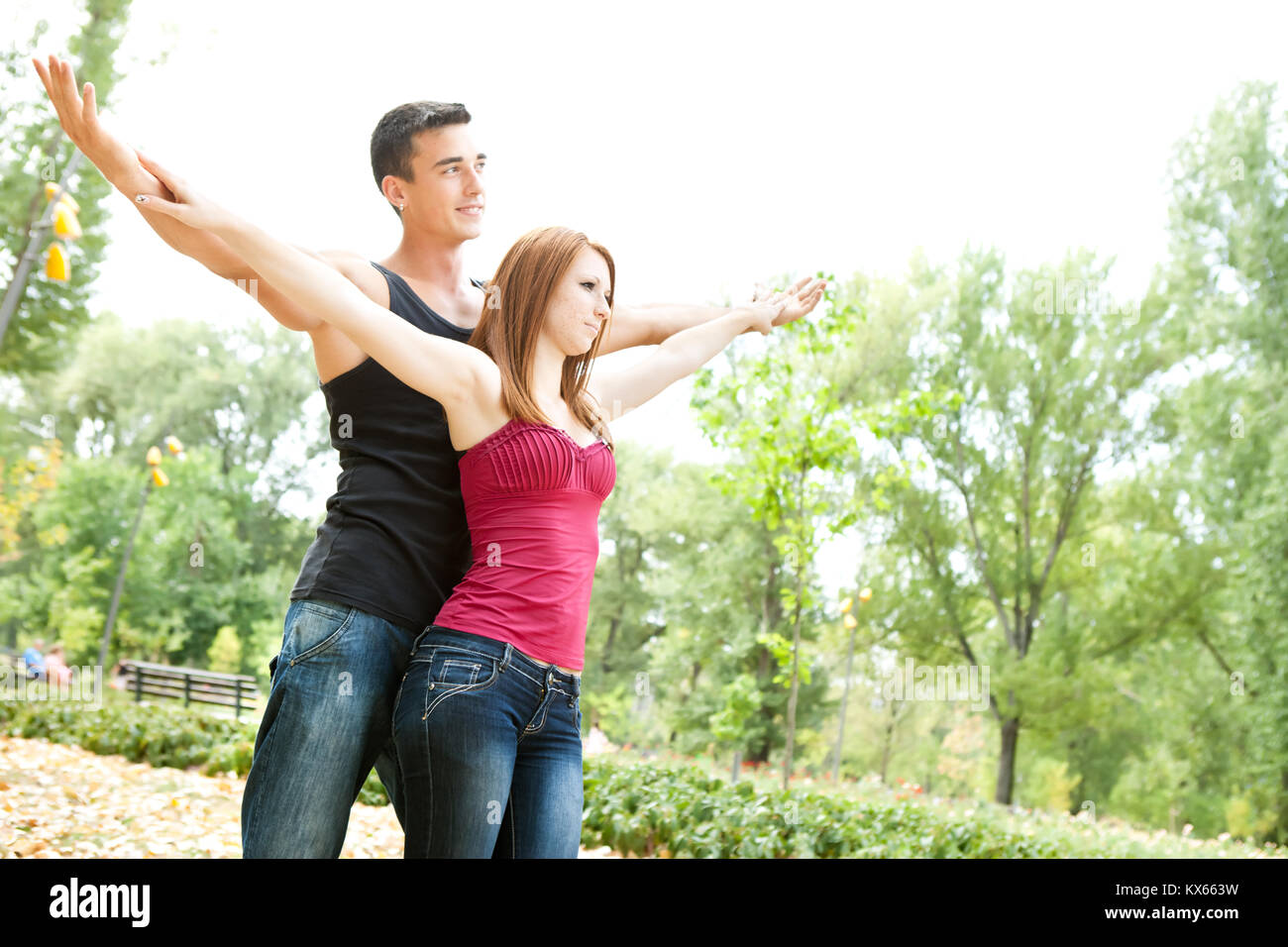 young couple standing with their arms outstretched in park Stock Photo ...