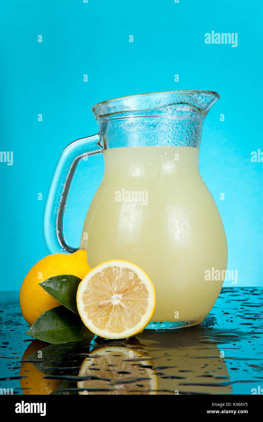 full Pitcher of fresh cool lemonade with lemon on blue background Stock ...