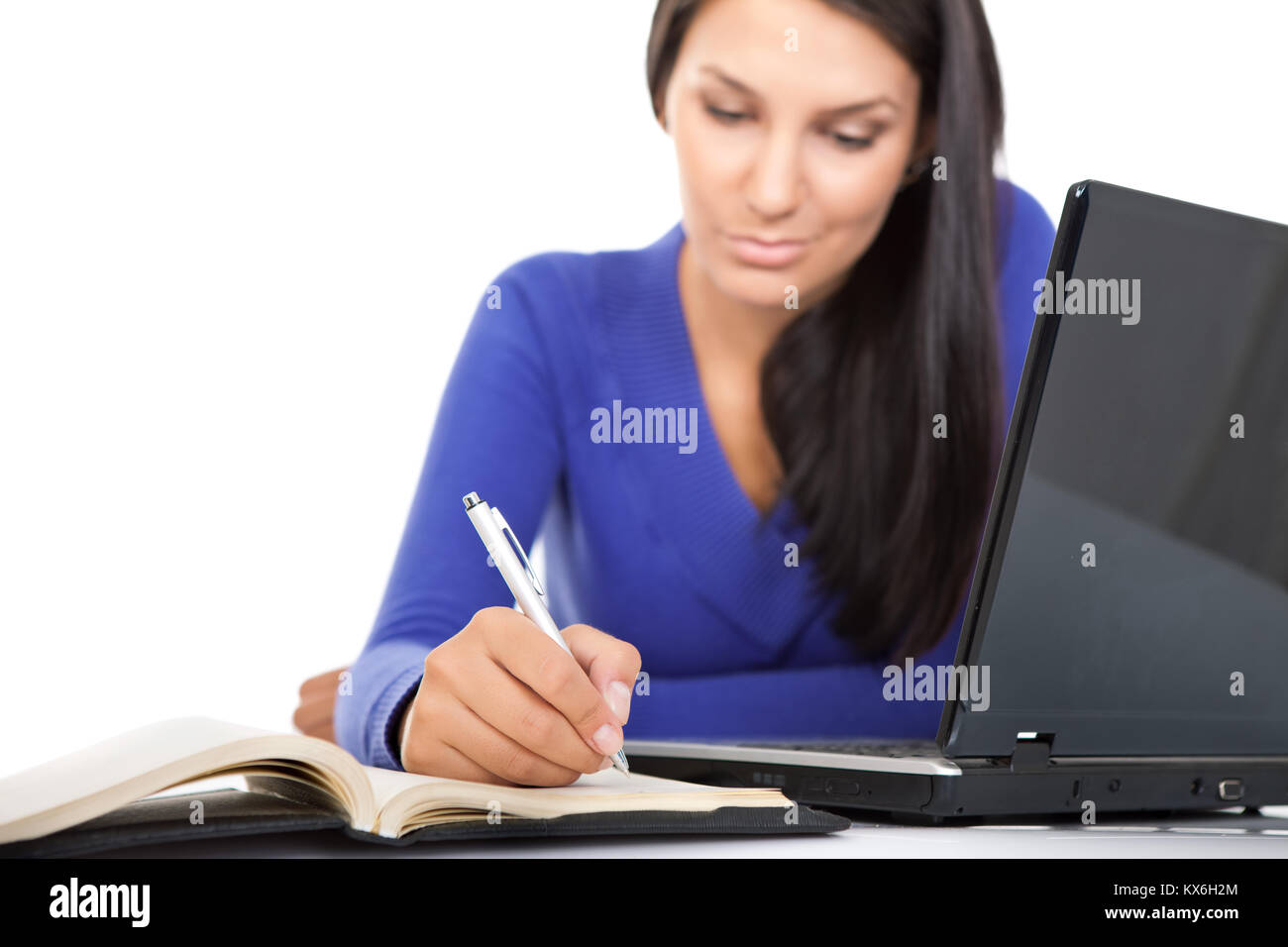hand with pen in focus, pretty female student with laptop and book ...
