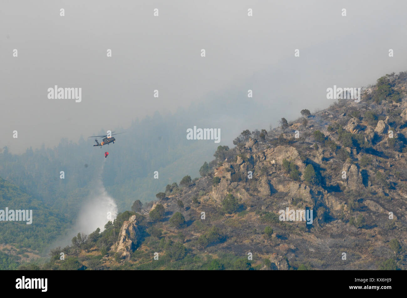 A Utah National Guard Blackhawk helicopter drops water along a ridge on ...