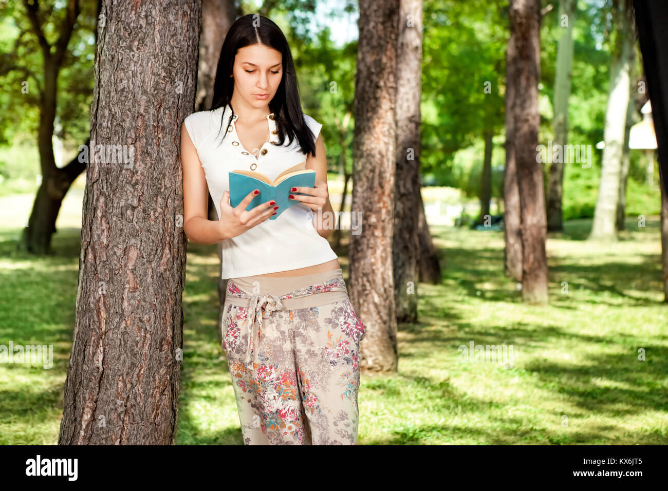young student girl reading book near tree in forest Stock Photo - Alamy