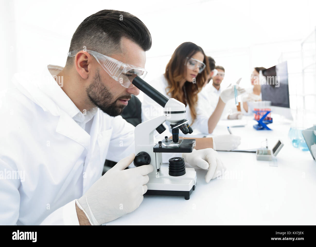 male lab technician looks at the sample under a microscope Stock Photo ...