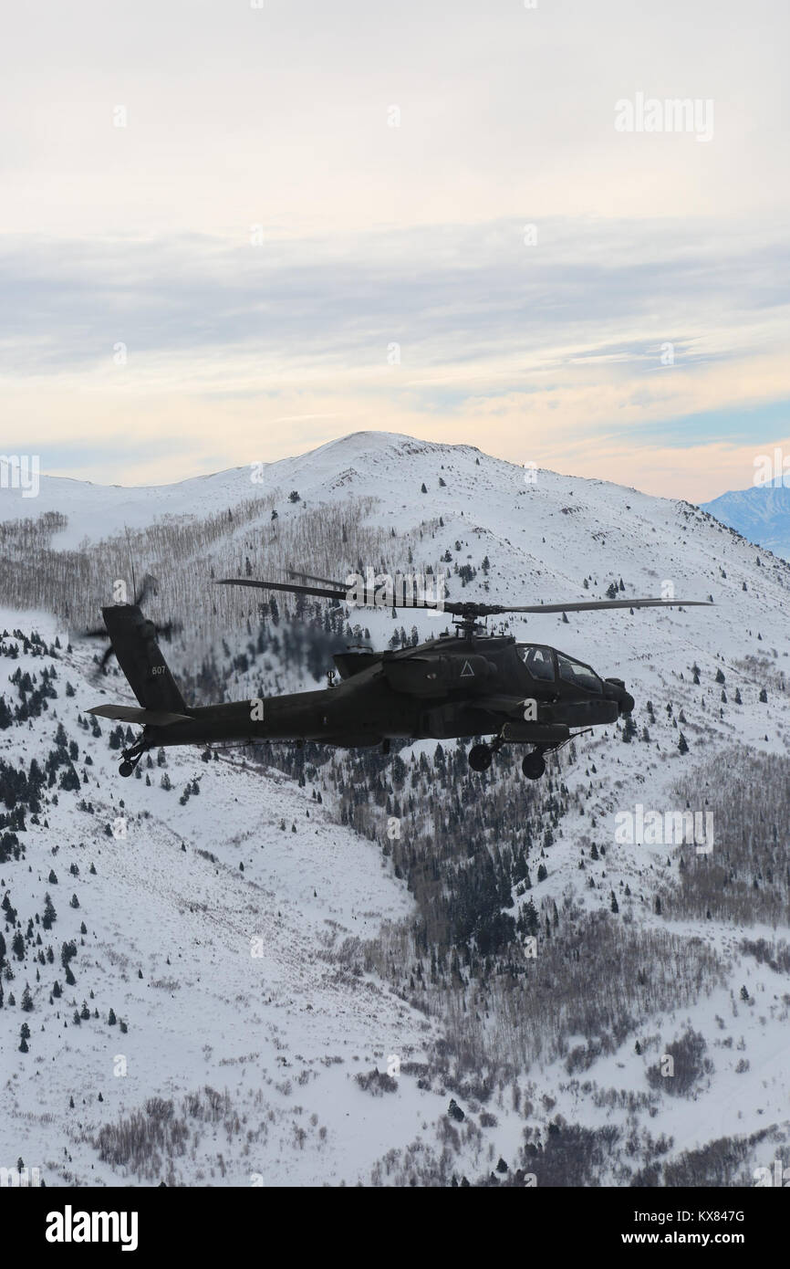 US Army National Guard flying AH-64 Apache military helicopter in snowy winter mountains Stock ...